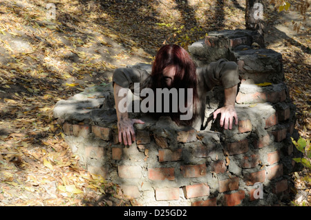 Horror woman crawling out of a brick well Stock Photo - Alamy