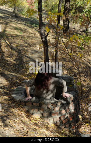 Horror woman crawling out of a brick well Stock Photo - Alamy