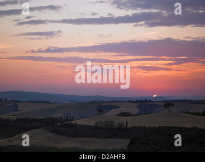 A serene landscape with the sun rising over a lush green field of grass ...