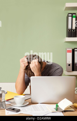 Anxious young Caucasian man working remotely on the computer sitting on ...