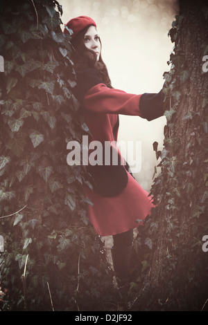 a woman with a red coat and hat between two trunks Stock Photo - Alamy