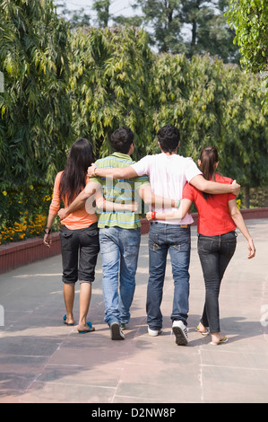 Rear view of couples walking on shore at beach during sunset Stock ...