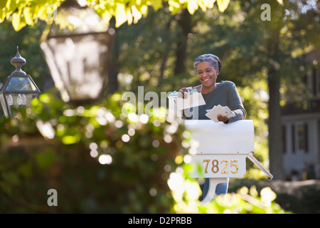 Woman reading mail while standing by mailbox Stock Photo - Alamy