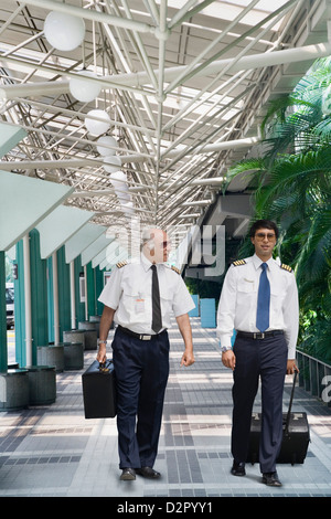 Two pilots carrying their luggage at an airport Stock Photo - Alamy