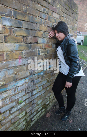 Upset and scared Asian girl leaning against a brick wall Stock Photo ...