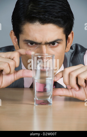 Young businessman with glass of water in hand reading newspaper at ...
