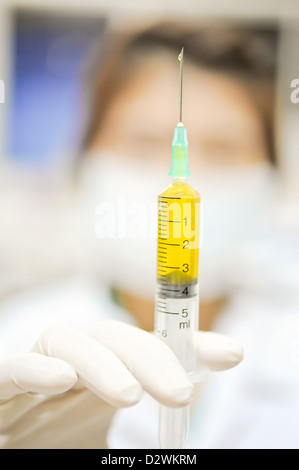 Male doctor using syringe to make injection to young female patient in ...