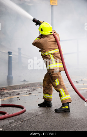 fireman with hose putting out fire Stock Photo - Alamy