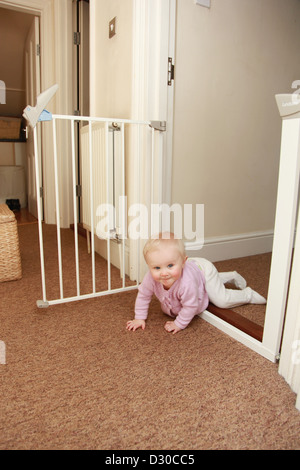Baby crawling through open safety gate Stock Photo - Alamy