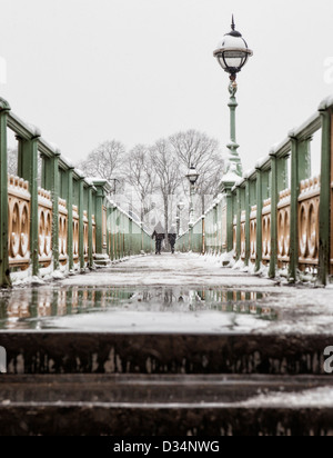People walk across the snow-covered frozen lake Elbsee under a clear ...