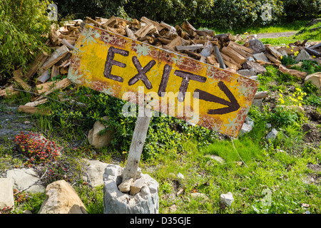 An exit sign pointing down toward the ground, hand painted in yellow ...