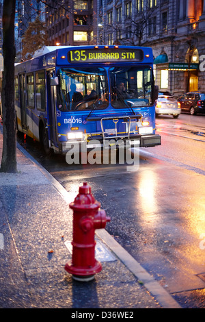 Vancouver city bus at stop on wet street in early evening in downtown ...