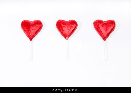 Three red hearts in a row cut from paper on white background, craft ...