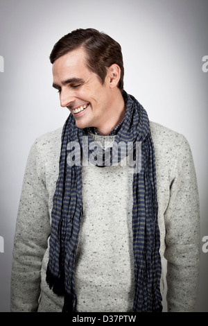 Smiling man wearing scarf looking away while standing against lake ...