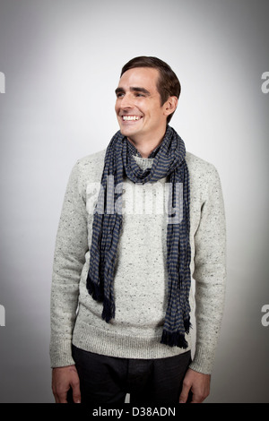 Smiling man wearing scarf looking away while standing against lake ...
