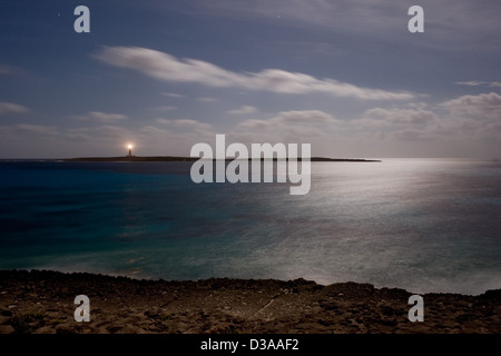 View of the lighthouse at Punta Prima with Clouds and sun above the sea ...