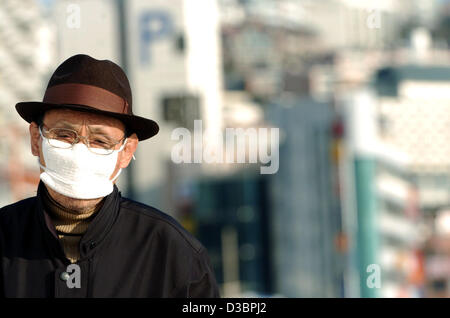 An elderly man wears his face mask below his nose and walks in a market ...