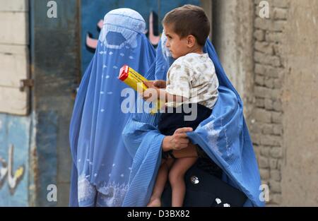 (dpa) - Two women wearing the traditional blue burka veil walk with a ...