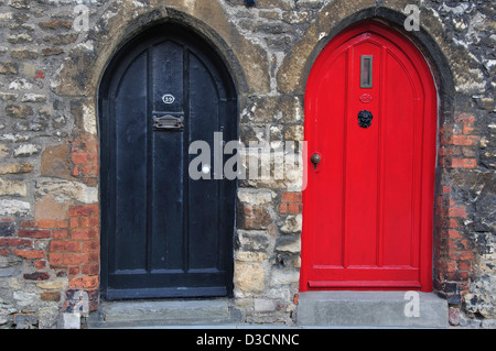 Two doors, one red, one black, and two upstairs windows side by side in ...