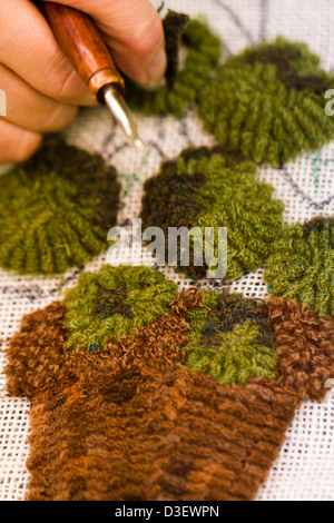 Hands work a hook in hug hooking craft Stock Photo - Alamy
