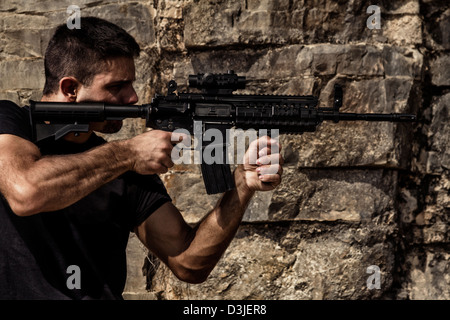 View of a menacing man pointing a machine gun in a black shirt and dark ...