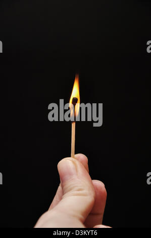 hand holding lit matchstick on black backgrounds Stock Photo - Alamy