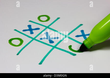 A close up of a game of Xs and Os on a note pad with colorful grids ...