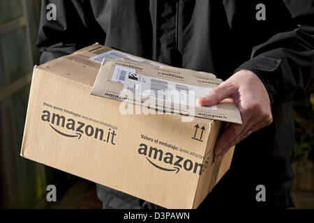 A man delivering an Amazon box with the Amazon smile logo in the UK ...
