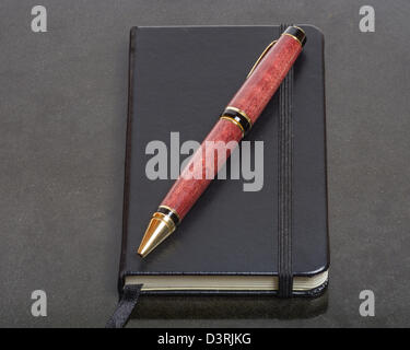 Fountain pen on a notebook. Black ink splash. Wooden table. Copy space ...