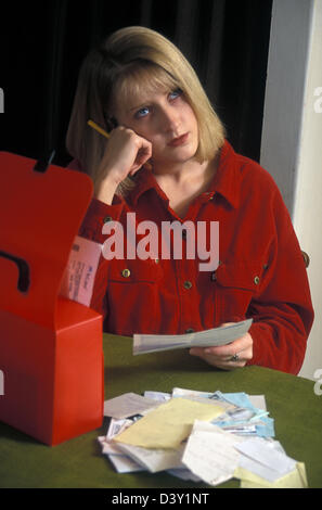 A woman with piles of bills and money Stock Photo - Alamy