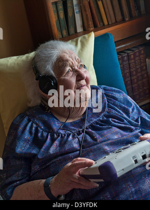 Elderly lady listening to an audio book, with a CD player designed for ...