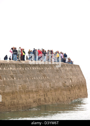 A crowd of people standing at end of the Cobb looking out to sea Stock ...
