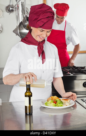 Female chef pouring oil on food in plate Stock Photo - Alamy
