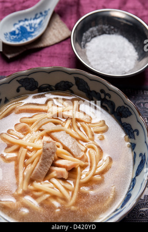 Warm chicken noodle soup in white ceramic bowl with carrot slices herbs ...