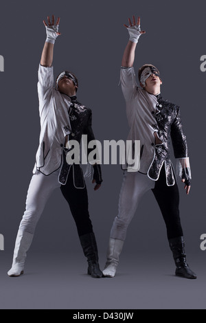 Full body of strong shirtless male acrobat performing coin trick with ...