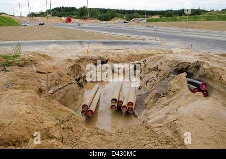 Pipe and cables in trench at road crossing laying pipelines. Building ...