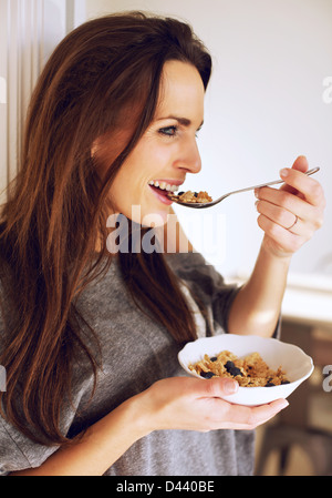 Brunette young woman eating breakfast sitting on the bed amazed and ...