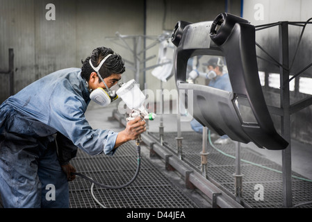 Coveralls worker with spray gun painting steel parts in painting ...