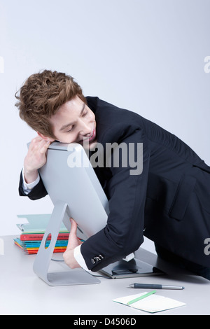 a man hugging a monitor on a desk Stock Photo - Alamy