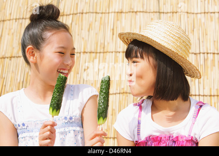 Two children eating fresh cucumbers in backyard Stock Photo - Alamy