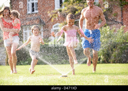 Mother and daughter running through sprinkler Stock Photo - Alamy