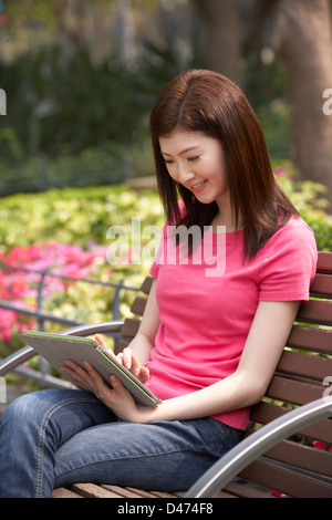 Happy young woman using tablet PC lying on bench Stock Photo - Alamy