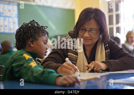 School child being helped by a volunteer teacher in reading Stock Photo ...