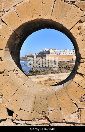 View through porthole in brick wall to the rock-strewn coast in front ...