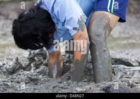 Young people sinking in mud while planting new tree for mangrove ...