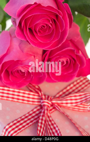 Pink roses resting on pink polka dot wrapped present with gingham ...
