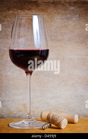 Glass of red wine on wooden table with the bottle in the background ...
