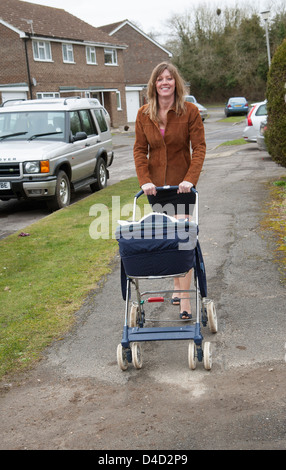 Mother walking and pushing pram Stock Photo - Alamy