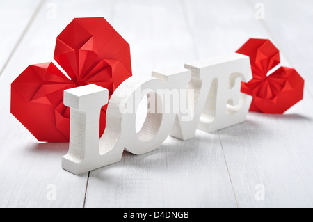 Red paper with word love and heart shapes on wooden table Stock Photo ...