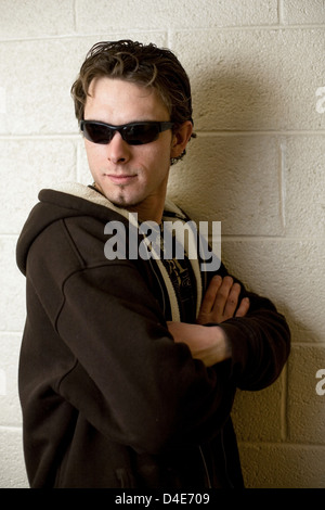 Young man leaning against a cinder block wall Stock Photo - Alamy